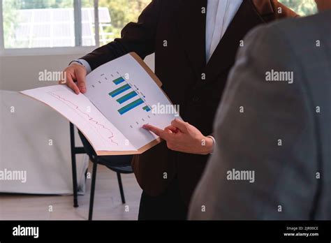 Two Unrecognizable Men In Suits Analyzing Performance Charts Of A Business Business Man