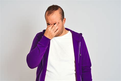 보라색 스웨트 셔츠를 입고 고립 된 흰색 배경에 서있는 젊은 남자는 피로와 두통을 느끼는 코와 눈을 문지르며 피곤합니다 스트레스와 좌절 개념 눈 신체 부분에 대한 스톡 사진