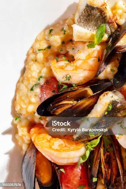 해산물과 로즈 와인 한 잔을 곁들인 프레골라 파스타 음식은 흰색의 세라믹 접시에 놓여 있고 칼은 근처에 있습니다 파스타 한