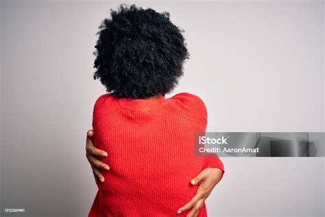 젊은 아름 다운 아프리카 계 미국인 Afro 여자 곱슬 머리 를 입고 빨간 캐주얼 스웨터 포옹 자신 포옹 자신 에서 뒤로 자기