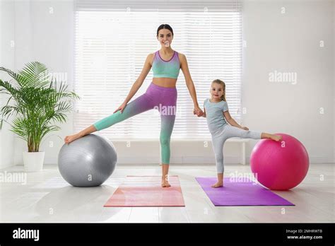 Woman And Daughter Doing Exercise With Fitness Balls At Home Stock
