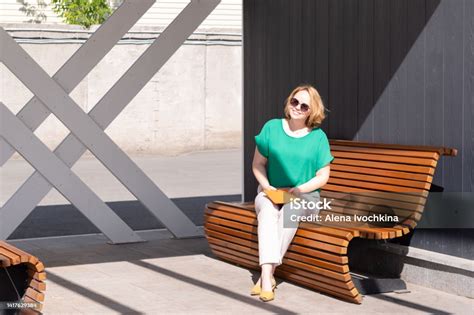 거리에서 현대적인 디지털 태블릿을 손에 들고 선글라스를 착용하고 웃는 학생 소녀의 초상화 거리의 벤치에 앉아있는 매력적인 소녀 온라인 교육 및 업무 도시에 대한 스톡 사진