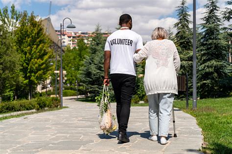 보호 얼굴 마스크에 젊은 남자의 팔을 들고 그 근처 지팡이와 함께 걷는 노인 여성 지팡이에 대한 스톡 사진 및 기타 이미지 지팡이 걷기 노인 주거시설 Istock