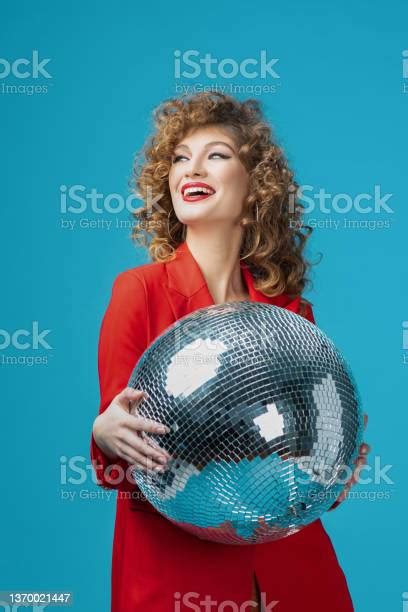 파란 배경 위에 고립 된 디스코 공과 함께 서있는 동안 파티를 갖는 빨간 드레스를 입은 즐거운 아름다운 여성의 초상화 귀여운에 대한 스톡 사진 및 기타 이미지 Istock