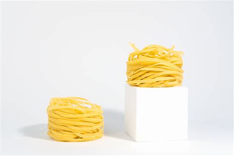 이탈리아 파스타 하얀 연단에 있는 스파게티 카펠리니는 단단한 그림자가 있는 흰색 회색 배경에 고립되어 있습니다 둥지의 형태로 파스타 파스타 음식의 창조적 인 사진 0명에