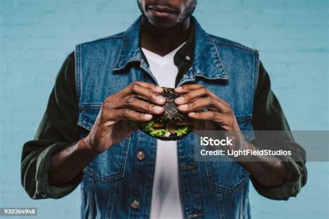 맛 있는 블랙 버거를 들고 하는 아프리카계 미국인 남자의 총 자른 건강에 좋지 않은 음식에 대한 스톡 사진 및 기타 이미지