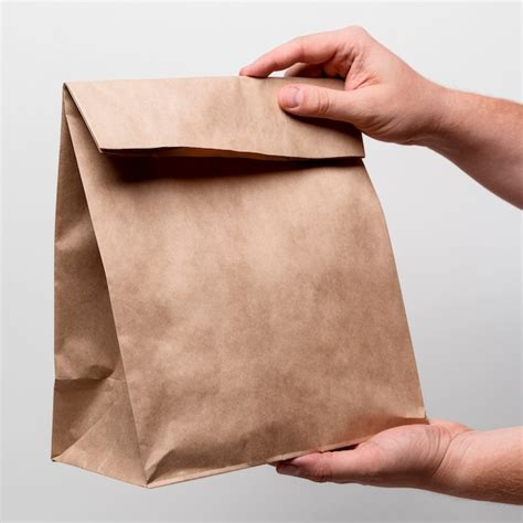 Manos De Primer Plano Sosteniendo Una Bolsa De Papel Foto Gratis