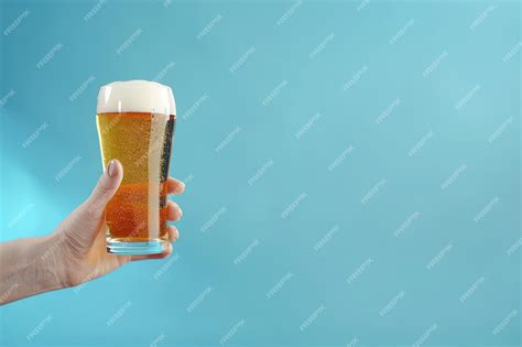 Holding A Glass Of Beer On A Blue Background Premium Ai Generated Image