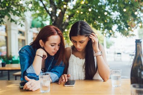 Dos amigas navegando en teléfonos móviles en street cafe Foto Premium