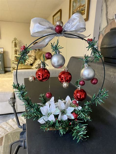 A Christmas Wreath With Ornaments Hanging From It S Centerpiece In A