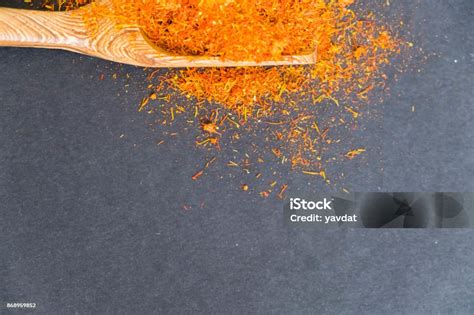 검은 배경에 사프란 향신료를 건조 원시 유기 암 꽃 술 가루 사프란 테이블에 흩어져 있습니다 검은 배경에 나무 숟가락에 레드