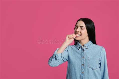 Young Woman Biting Her Nails On Pink Background Space For Text Stock