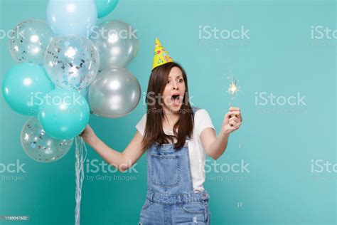 축 하 파란색 청록색 배경에 고립 된 다채로운 공기 풍선을 들고 불꽃을 굽기 찾고 생일 모자에 비명 여자 충격 생일 휴일 파티
