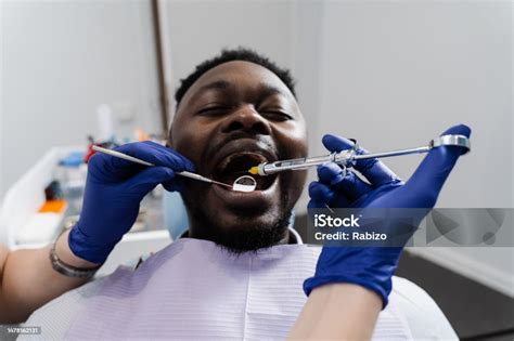 치과 의사는 아프리카 남자 환자를 위해 병든 치아의 마취 주사기를 주입합니다 충치 치료 25 29세에 대한 스톡 사진 및 기타 이미지 25 29세 30 34세 건강