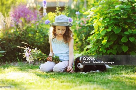 행복 한 아이 여자 편안한 그녀의 발 바리 강아지와 여름 정원에서 정원사 모자를 착용 하 고 꽃의 꽃다발을 들고 배경에 피 사계절입니다 강아지 개에 대한 스톡 사진 및 기타
