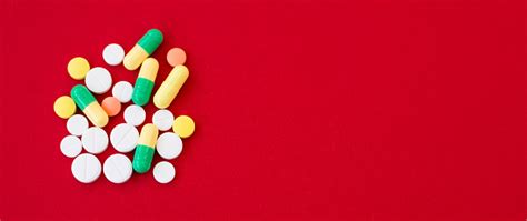 赤の背景に丸薬やカプセルと医療の背景薬薬の丸薬の盛り合わせ 錠剤様々な様々な薬の錠剤や丸薬の異なる色のヒープ医療トップビュー