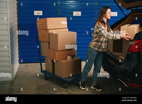 Full Length Of Lady With Cardboard Boxes Near Trunk Of The Car Into Warehouse Stock Photo Alamy