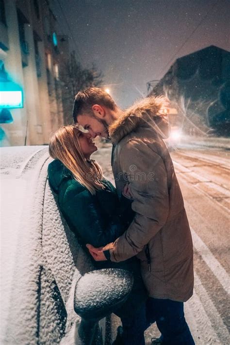 Young Adult Couple Kissing Each Other On Snow Covered Street Stock