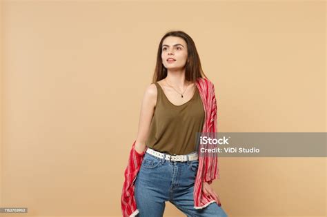 캐주얼 한 옷에 매력적인 젊은 여자의 초상화와 스튜디오에서 파스텔 베이 지 벽 배경에 고립 된 옆에 찾고 사람들은 진심으로 감정
