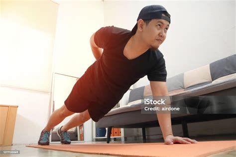 새로운 정상적인 라이프 스타일 실내 홈 운동 한 쪽 팔 푸시 업 판자 위치에 건강을 유지하기 위해 집에서 운동을하는 아시아 남성