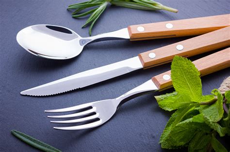 칼 세트입니다 칼 숟가락 슬레이트 돌에 포크 로즈마리와 민트가 있는 크립토클러 검은 색 배경입니다 공간을 복사합니다 맨 위 보기