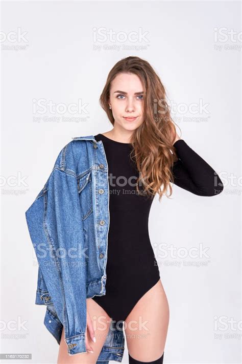 유행 데님 재킷 검은 바디 수트 흰색 배경에 스튜디오에서 포즈를 취하는 검은 스타킹을 입고 젊은 매력적인 세련된 미소 소녀 귀여운에 대한 스톡 사진 및 기타 이미지 Istock