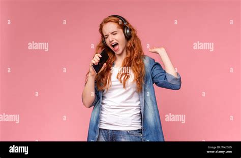 Emotional Redhead Girl Singing Into Smartphone Like Microphone Stock