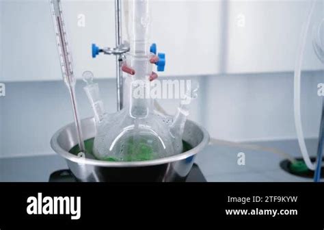 Misted Glass Flask And Thermometer In A Bowl Green Liquid Boils In The Flask Camera Moves To