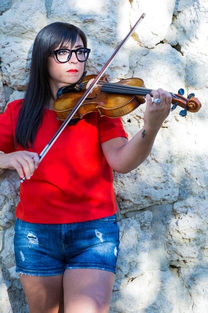 Premium Photo Woman Playing Violin Against Stone Wall