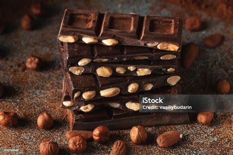 暗い背景にココアパウダーを振りかけたナッツ入りのダークチョコレートとミルクチョコレート おやつのストックフォトや画像を多数ご用意