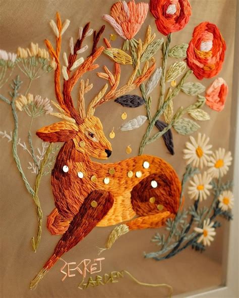 Вышитый олень с цветами и листьями на фоне ткани