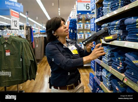 A Female Associate Uses A Telxon Handheld Scanner To Read EPC RFID Labels On Clothing At A
