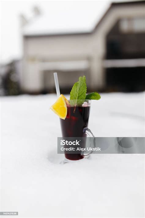 눈 속에서 멀드 와인 유리 머그잔에 담긴 Mulled 와인 오렌지와 사과가 든 뜨거운 적포도주 계피가 든 향신료 유리에 쏟아집니다 아름 다운 흰색 배경입니다 공간을