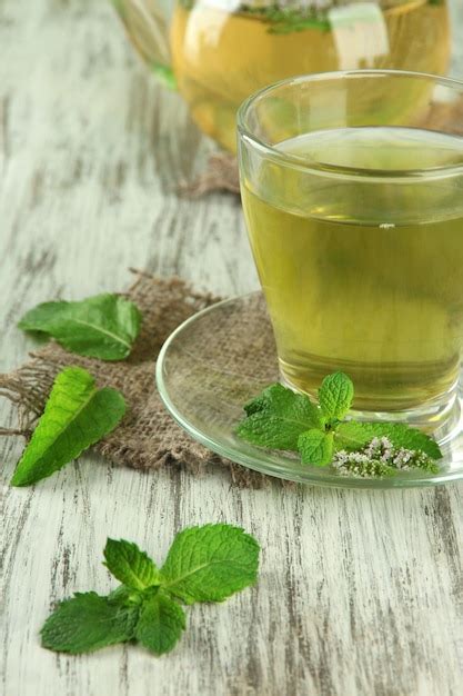 Tetera Y Taza De Té De Hierbas Con Flores De Menta Fresca En La Mesa De Madera Foto Premium
