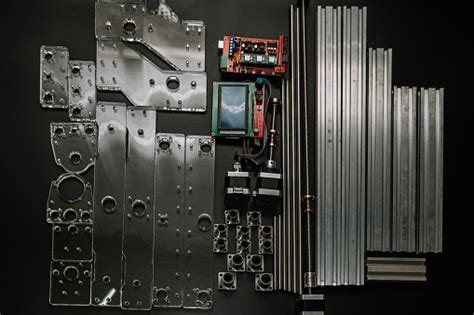 ชุดของชิ้นส่วนสําหรับเครื่องเลเซอร์บนพื้นหลังสีดํา แสงไฟเงิน วางแบนคณะ