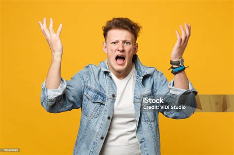 카메라를 찾고 데님 캐주얼 복장에 자극 비명 젊은 남자의 초상화 노란 오렌지 배경에 고립 된 손을 확산 사람들은 진심으로 감정 라이프 스타일 개념입니다 복사 공간을 모의