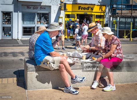 Two Retired And Elderly Couples Sit To Eat Take Away Fish And Chips