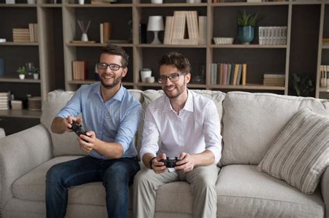 Two Millennial Twin Brothers Sitting On Sofa Playing Computer Videogame Stock Photo Image Of