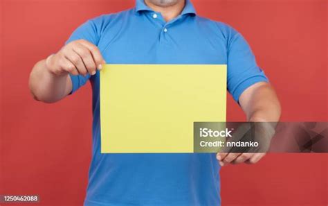 파란색 옷을 입은 남자가 빨간 배경에 노란색 종이의 빈 시트를 들고 공란에 대한 스톡 사진 및 기타 이미지 공란 광고 노랑 Istock