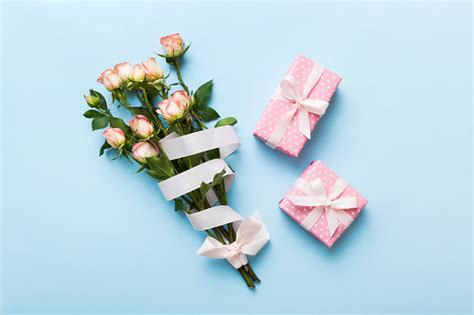 분홍색 장미 꽃과 선물 상자가 컬러 테이블 배경 위에 있는 디자인 컨셉 해피 홀리데이 어머니의 날 생일 개념 낭만적 인 플랫