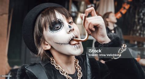 할로윈을 축하하는 아름다운 무서운 어린 소녀 구미 벌레를 츄잉 무서운 얼굴 메이크업과 마녀 의상 세련된 이미지 공포 거리에서