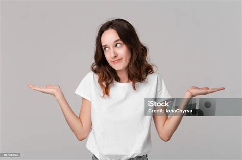 예쁜 갈색 머리 여자 에 흰색 티 어깨를 으쓱 그녀의 어깨 Beacause 그녀는 회색 배경 위에 고립 된 서 대답을 모른다 광고 의 공간을 복사합니다 어깨를 으쓱거림에