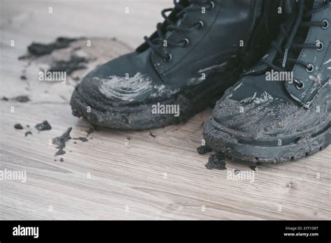 Muddy Black Boots And Muddy Footprints On A Wooden Floor Leaving A