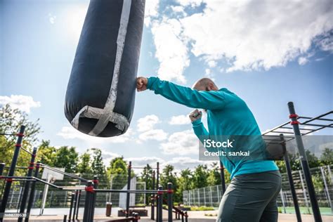 Mature Man Hitting Punching Bag At The Outdoors Sports Ground Stock