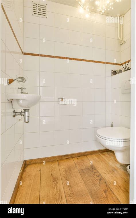 Wall Hung Toilet And Small Sink In Lavatory Room With White Tile Stock