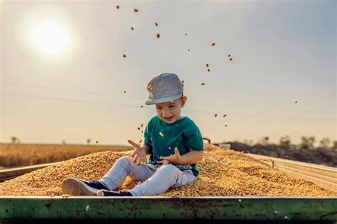 Premium Photo An Excited Little Farmer Boy Sits In A Tractor Trailer