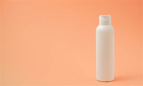 화이트 퓨어 선탠 로션 바디 크림 샴푸 또는 자외선 차단제 병 포장 모형 흰색 병과 주황색 배경 최소한의 여름 스킨케어와 자외선 차단 컨셉 텍스트에 배치합니다 모형에 대한