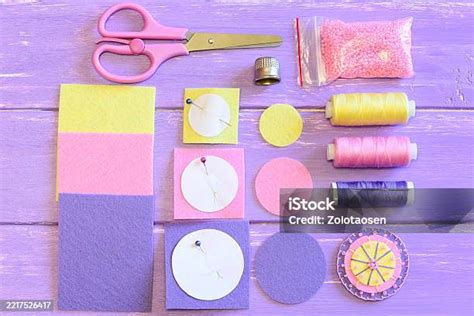 펠트와 구슬 색색의 펠트 원과 시트 가위 종이 템플릿 실 스풀 바늘 나무 테이블에 분홍색 구슬로 만든 귀여운 꽃 재봉 지침 상의
