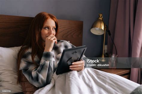 슬픔에 잠긴 젊은 여성이 담요 아래 침대에 누워 액자에 사진을 들고 울고 있는 모습 사랑으로 사진을 만지는 모습 25 29세에 대한 스톡 사진 및 기타 이미지 Istock