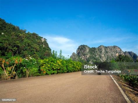 녹색 나무와 옆에 꽃 사이의 빈 시골 시골 도로 화창한 날에 푸른 하늘을 배경으로 작은 돌 산으로 향하는 길 0명에 대한 스톡 사진 및 기타 이미지 Istock